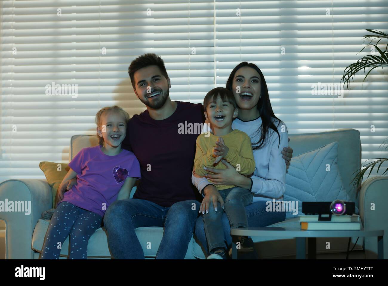 Happy family watching movie using video projector at home Stock Photo ...