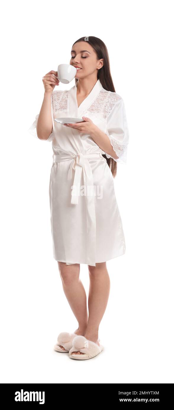 Young woman in silk robe with cup of beverage on white background Stock ...
