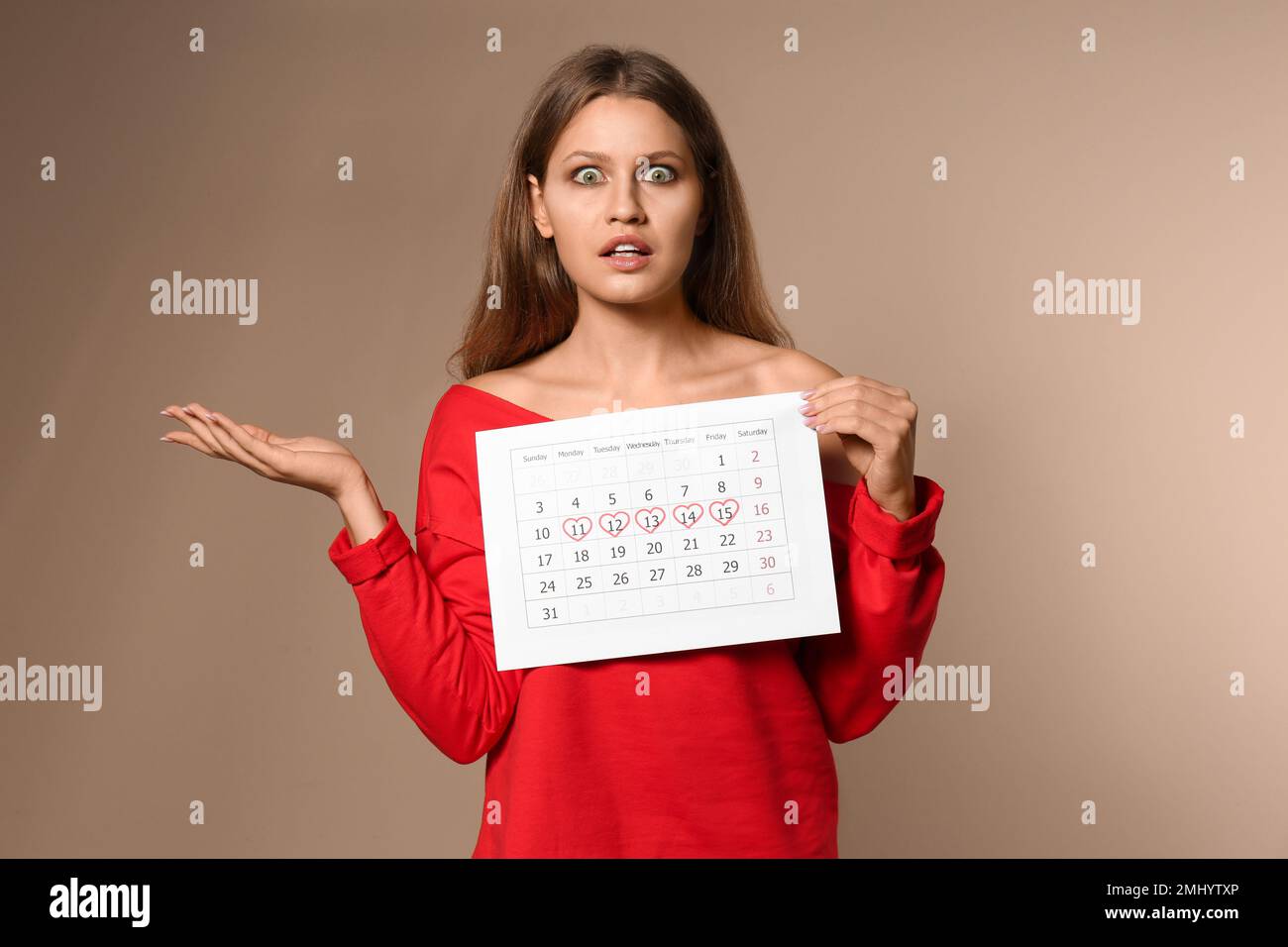 Emotional young woman holding calendar with marked menstrual cycle days ...