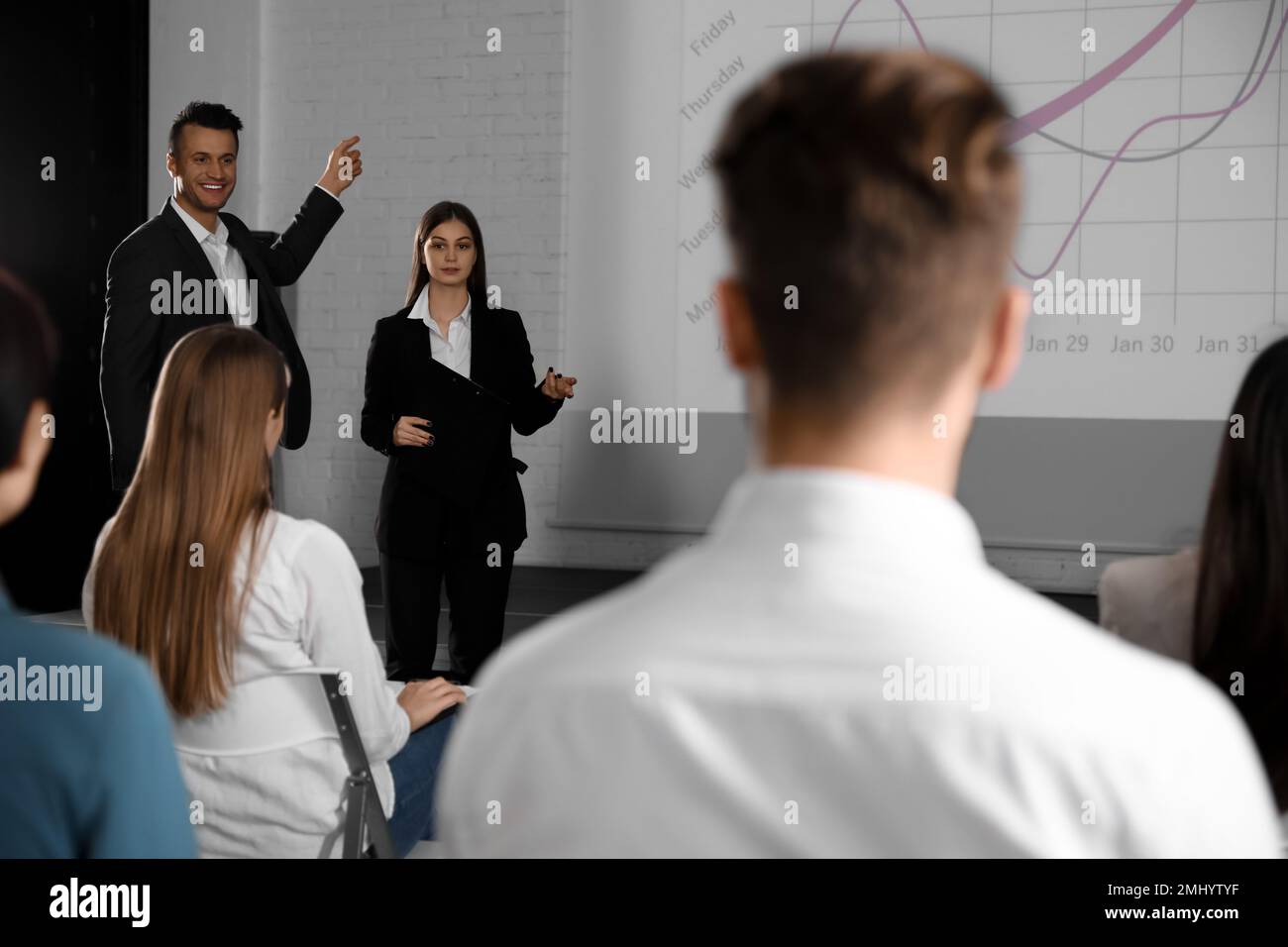 Business trainers giving lecture in conference room with projection ...