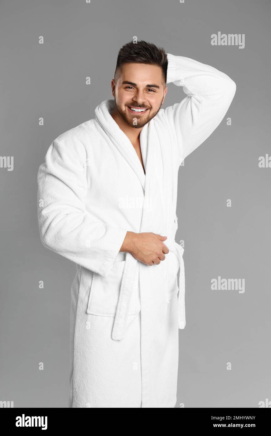 Happy young man in bathrobe on grey background Stock Photo - Alamy
