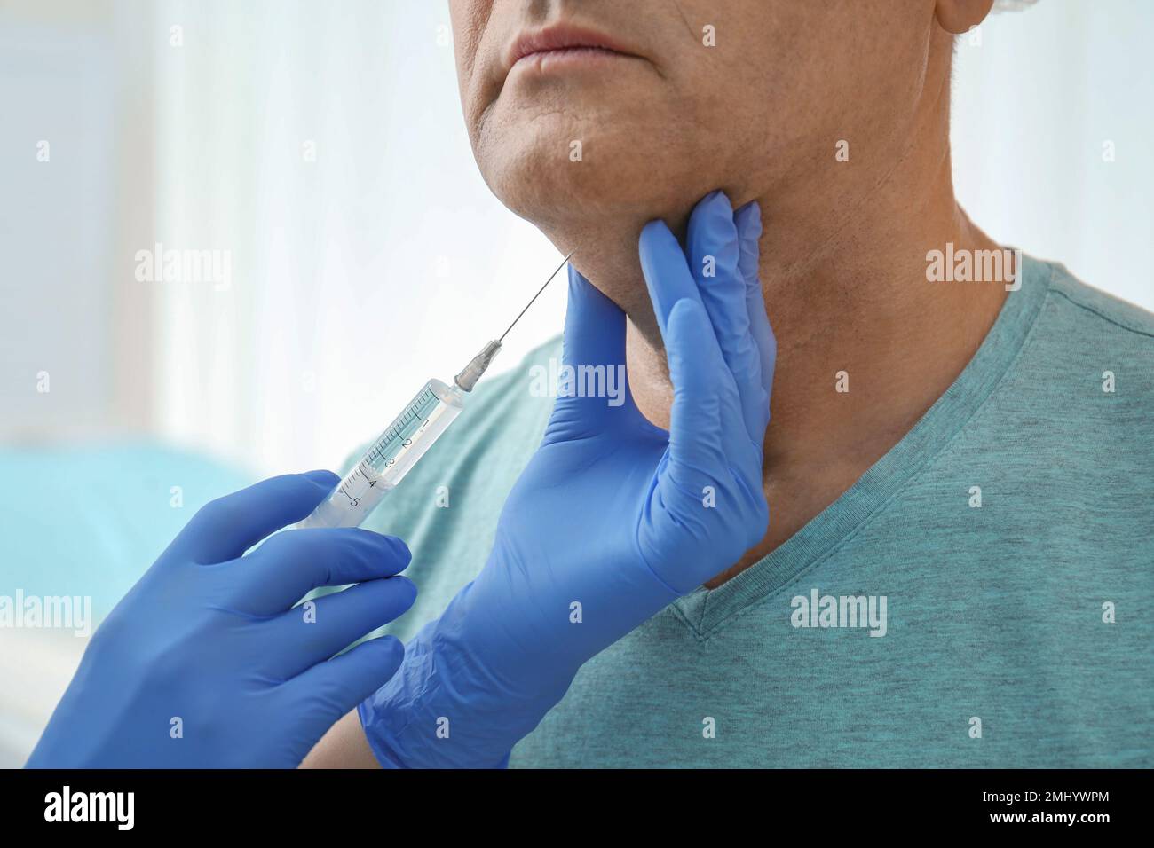 Mature man with double chin receiving injection in clinic, closeup ...