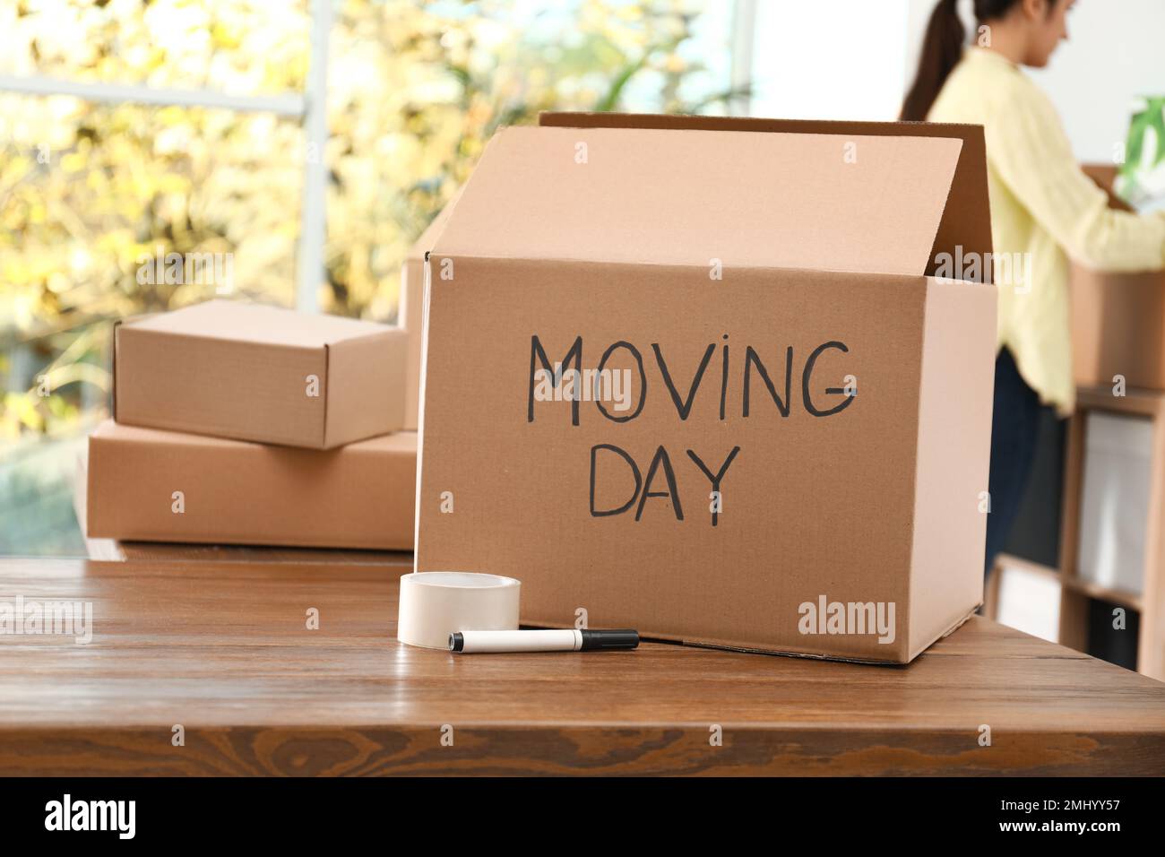 Cardboard box with words MOVING DAY and packaging items on wooden table ...