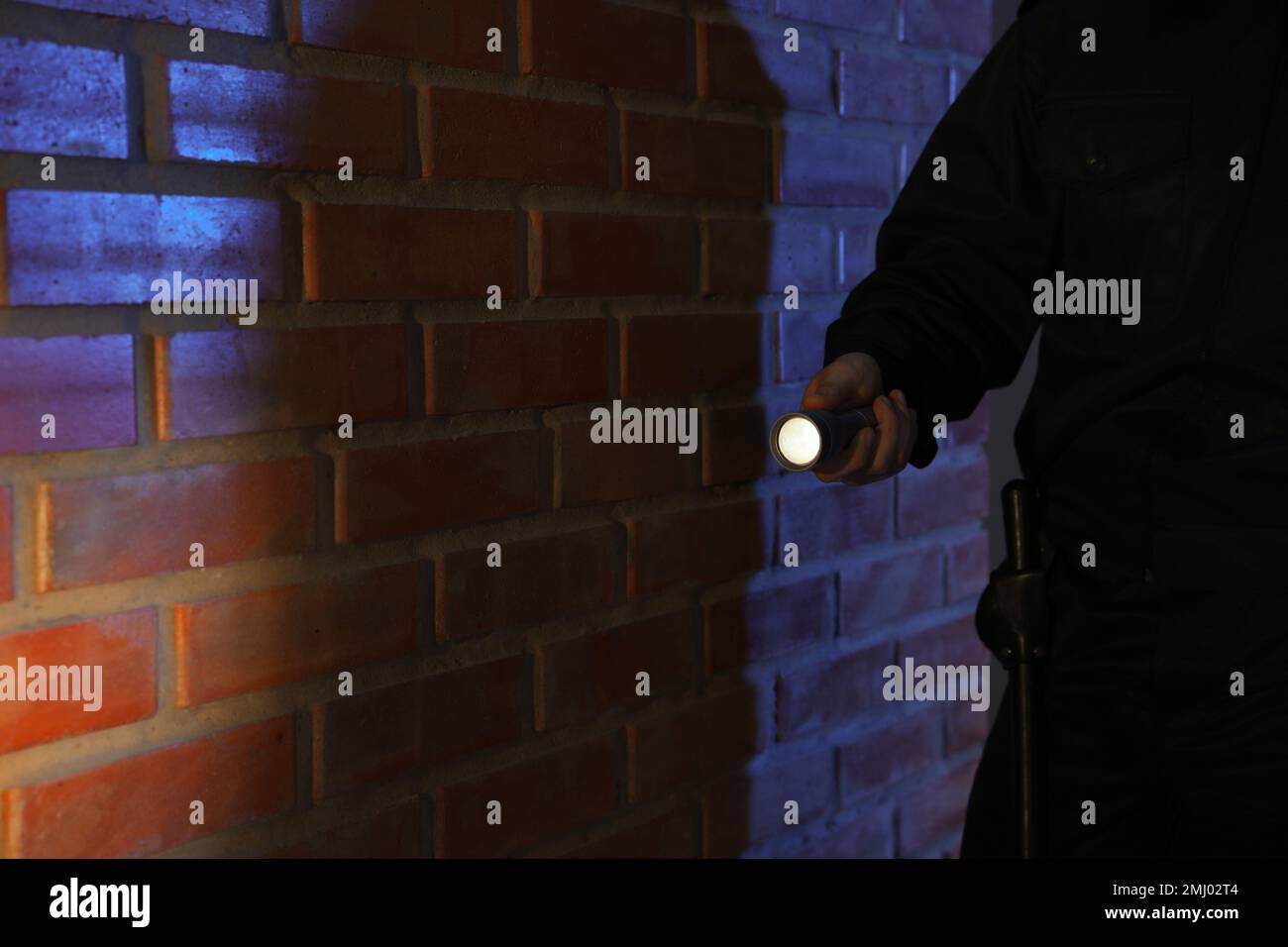 Male security guard with flashlight near brick wall in darkness Stock ...
