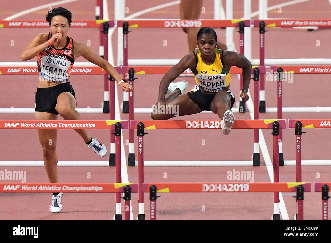 Megan Tapper, of Jamaica, clears a hurdle, followed by Asuka Terada, of ...