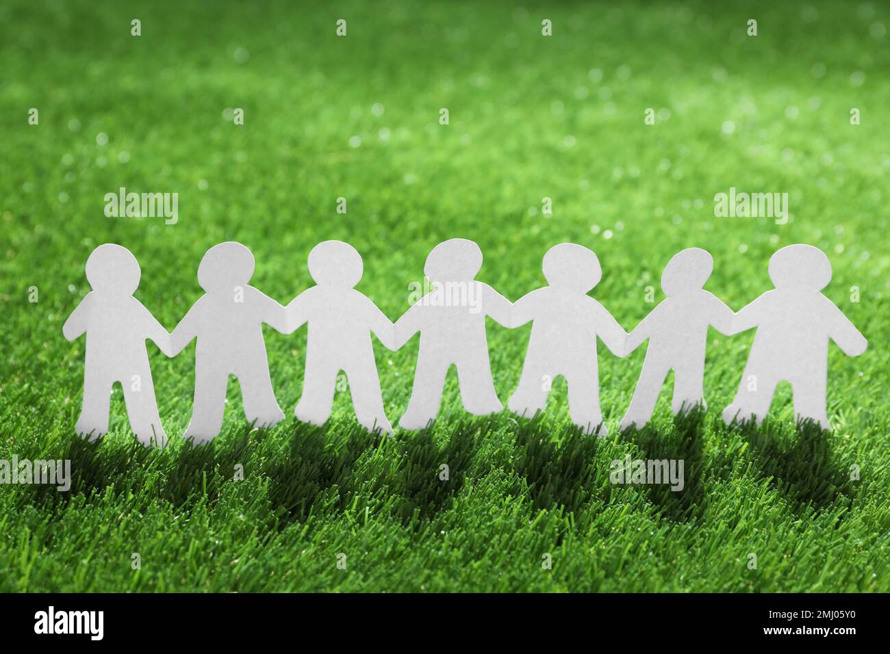 Paper people chain on green grass. Unity concept Stock Photo - Alamy