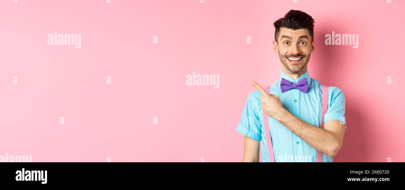 Portrait of handsome happy man showing logo, pointing left and smiling ...