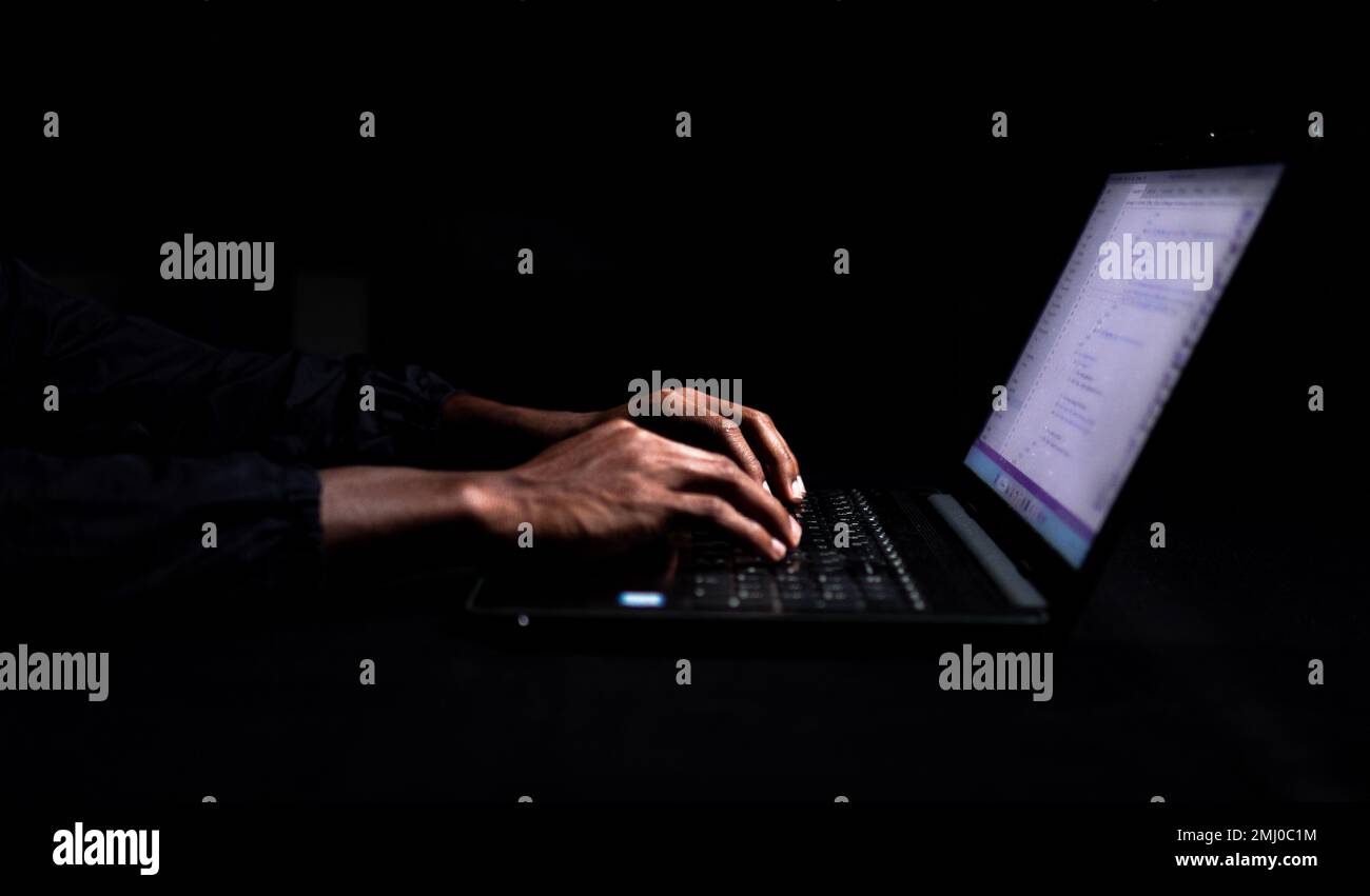 Hands typing out on laptop in dark room Stock Photo - Alamy