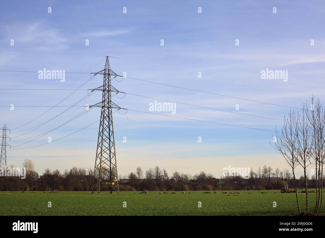 Cultivated field with electricity pylons and over head cables on a ...