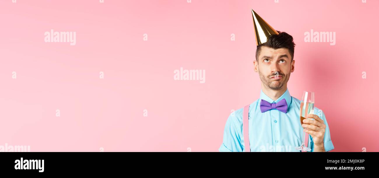 Holidays and celebration concept. Grumpy guy wearing birthday party hat ...