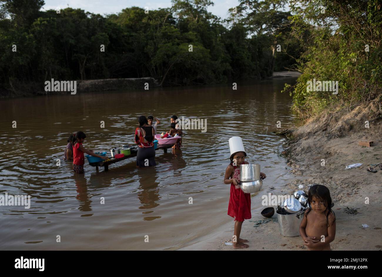 In this Sept. 2, 2019 photo, a girl carries pots washed by her mother ...