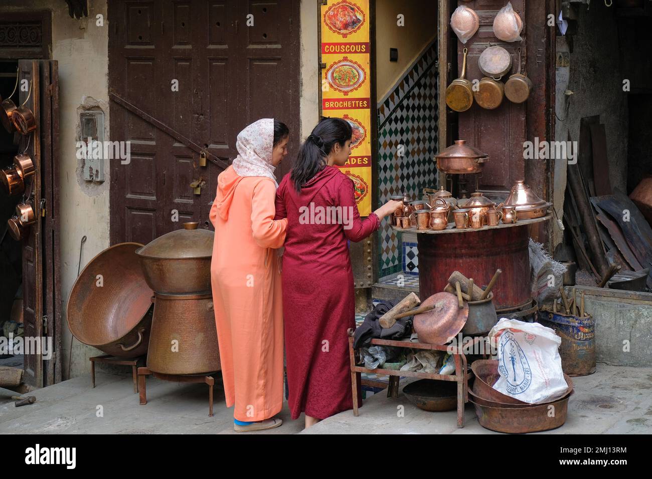 Fez, Morocco - two covered muslim women check out copperwares in Seffarine Square. Shop with ...