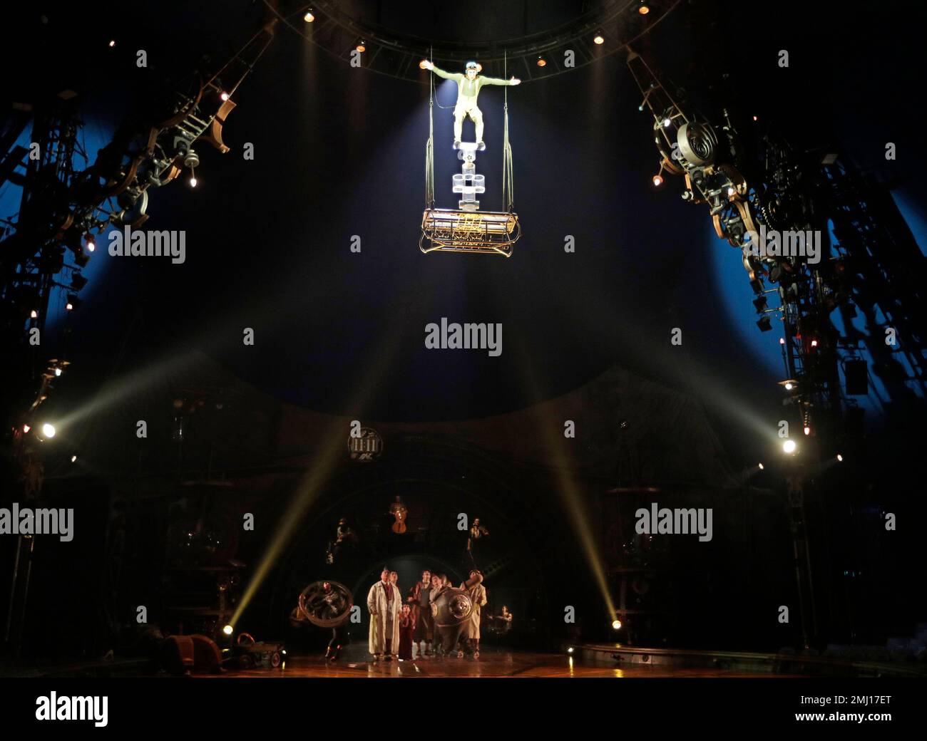 A performer balances on a stack of cylinders high above the floor ...