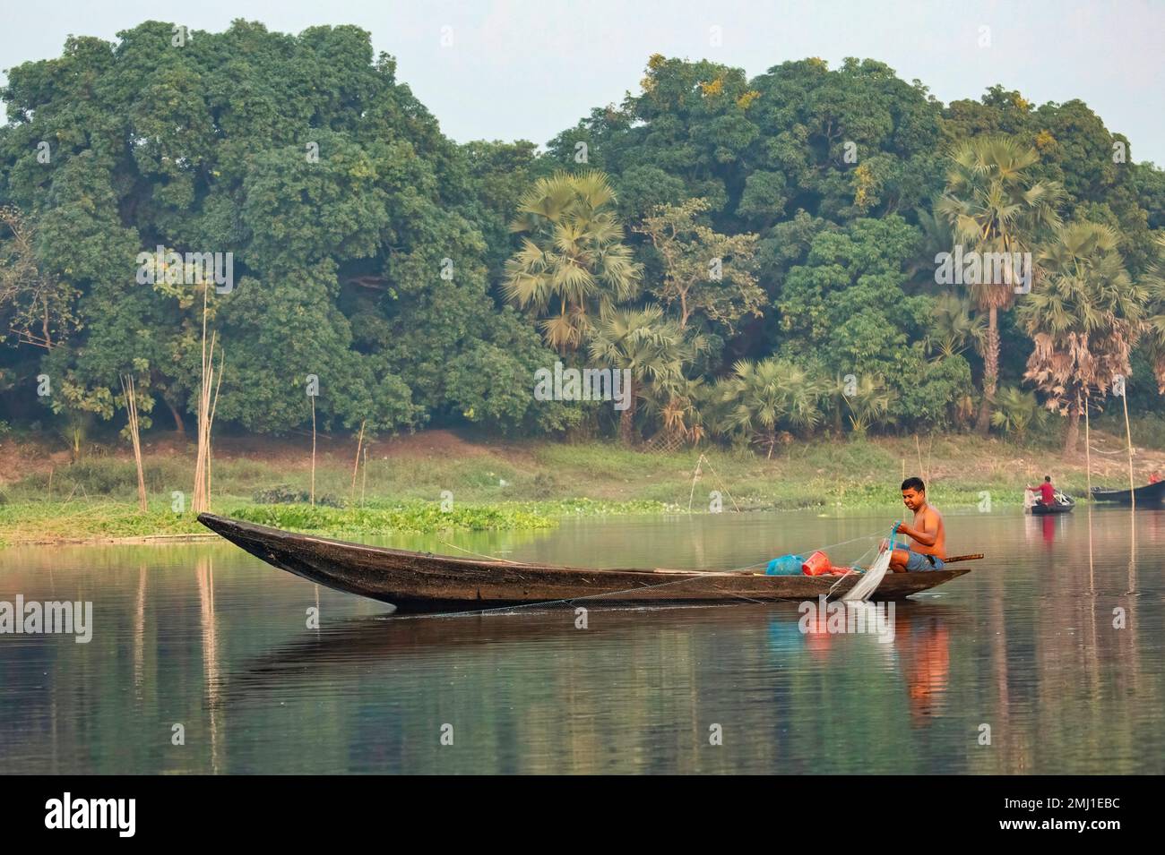 Man sitting on his boat fishing on river Ganges at in the estuary ...