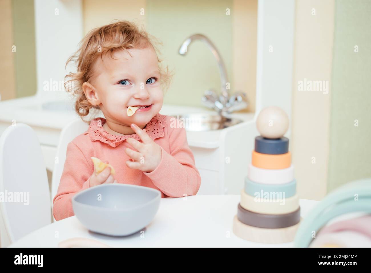 Happy child eating pasta in kindergarten at the table Stock Photo - Alamy