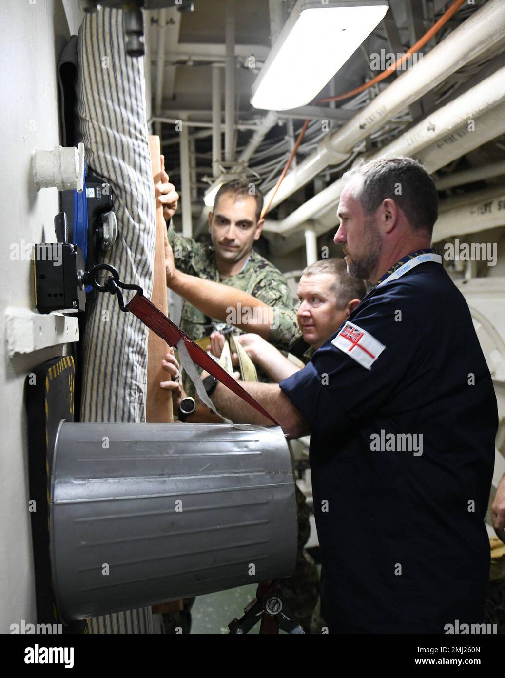 United Kingdom (UK) Royal Navy Cmdr. Derek Powles (right) assists Petty ...