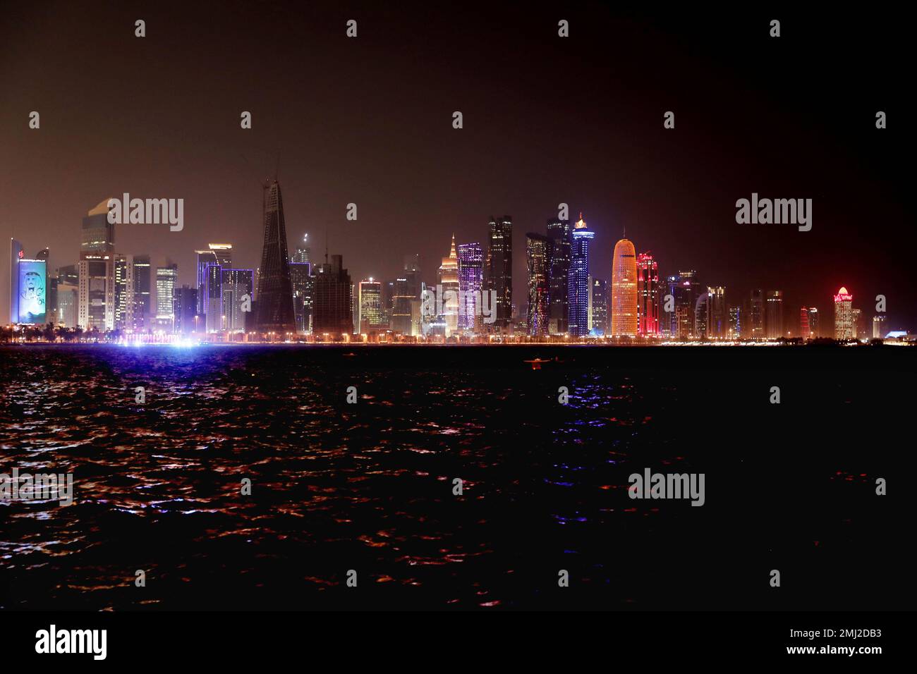 The Corniche waterfront promenade with a night view of skyline in Doha ...