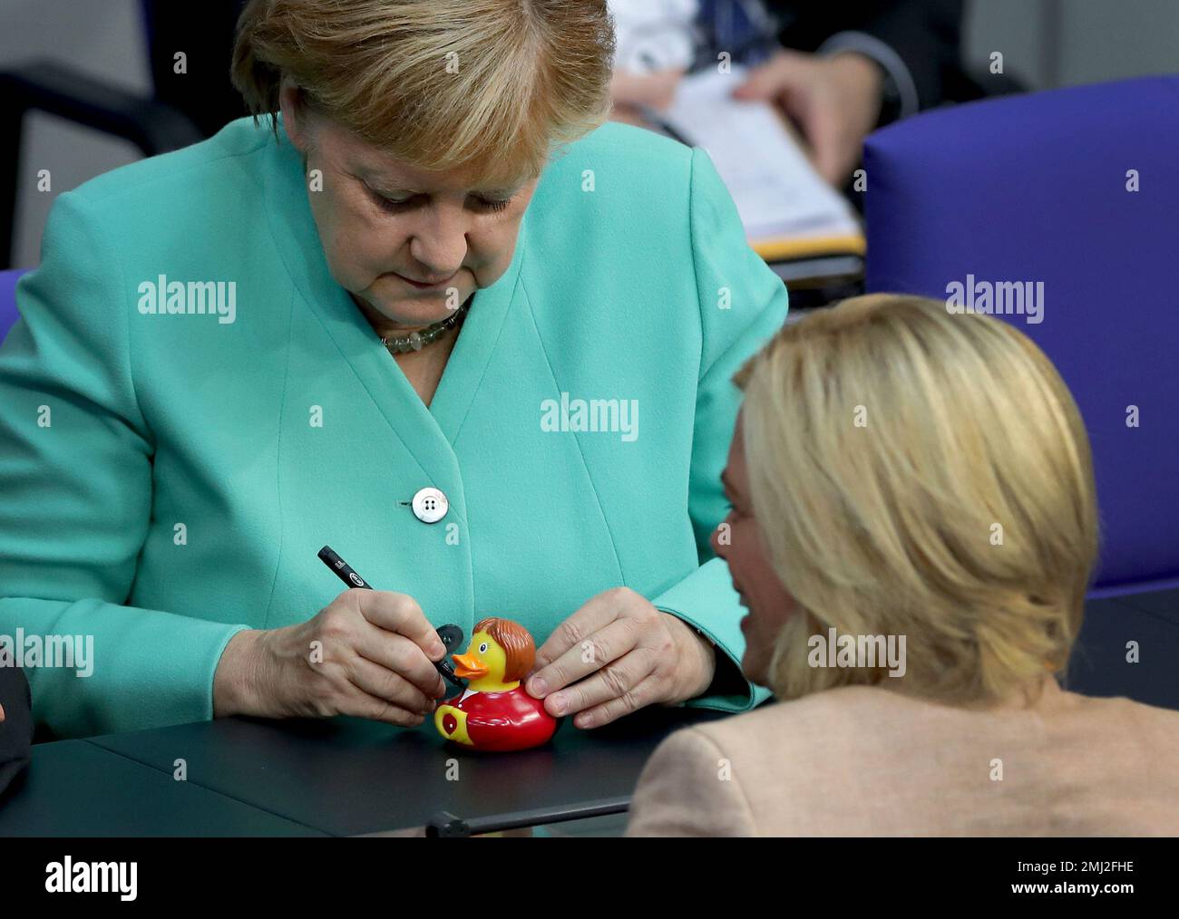 German Chancellor Angela Merkel, left, signs a rubber duck for German ...