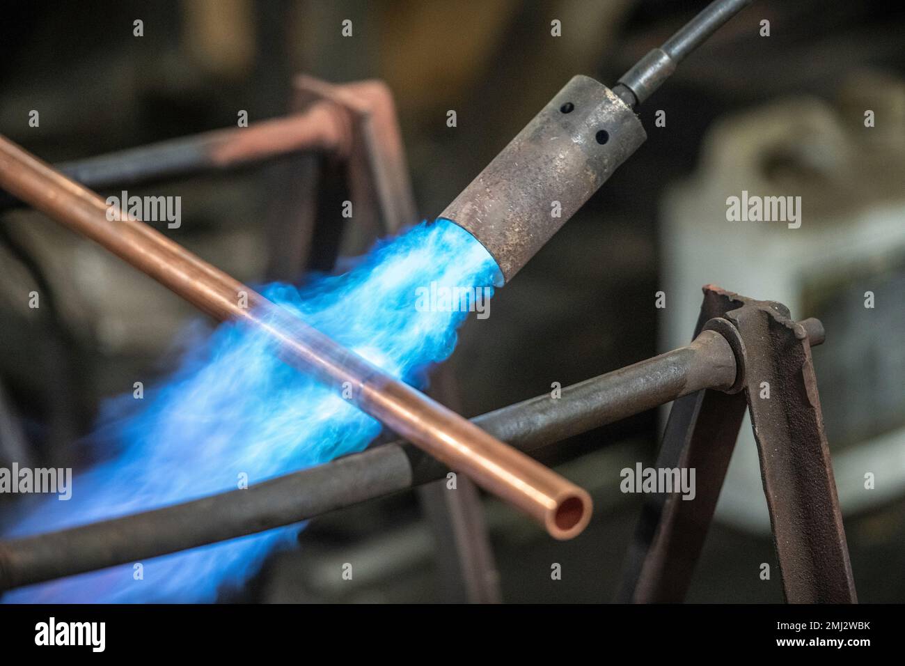 Light blowtorch blasts copper tube with hot blue flame to anneal it at ...