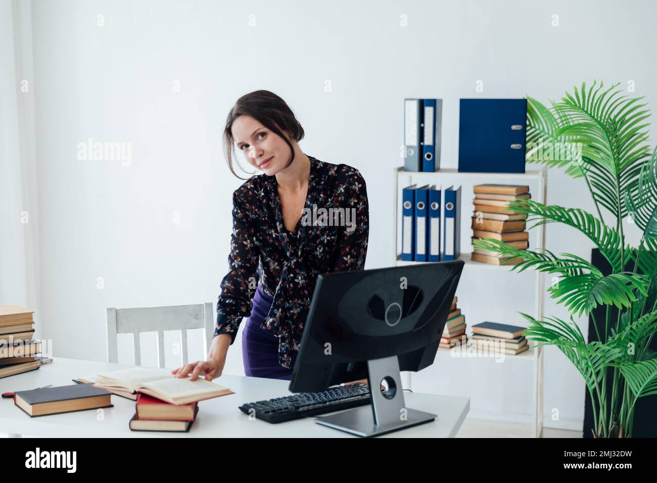 female teacher office worker standing at a desk with books and a ...