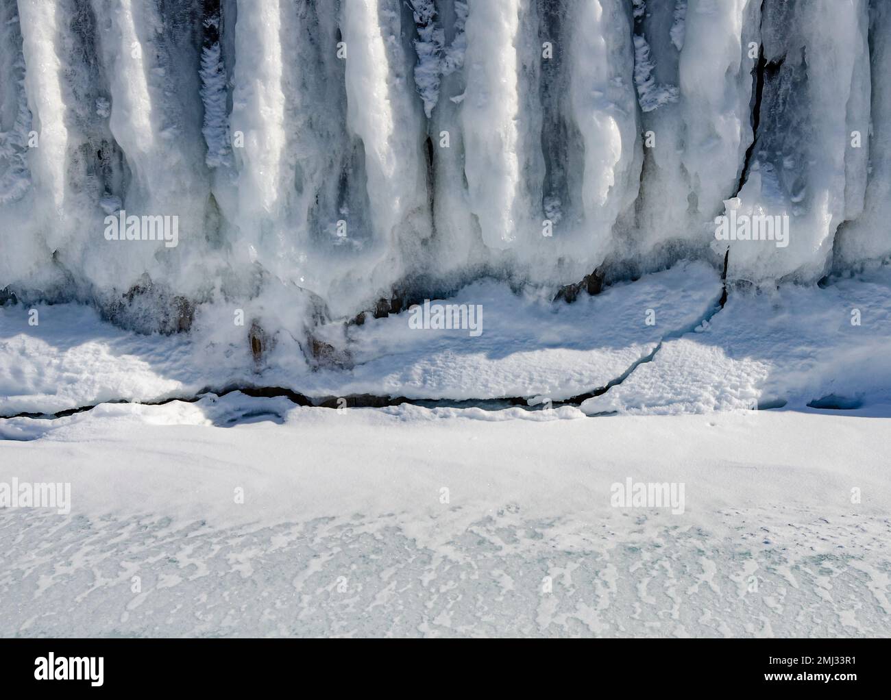 Ice forms on the bottom of a side of a buidling on the shore dock area ...