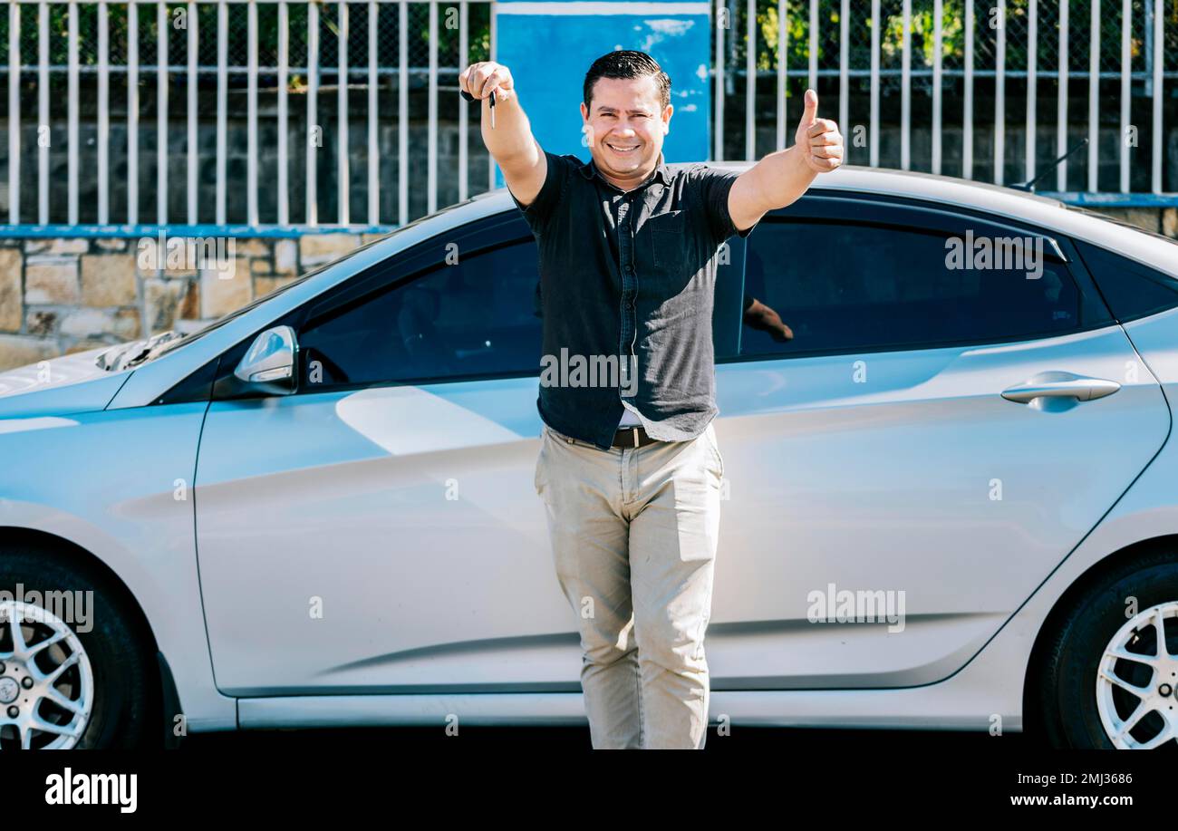 Driver leaning on the car showing the key, Male driver standing next to ...
