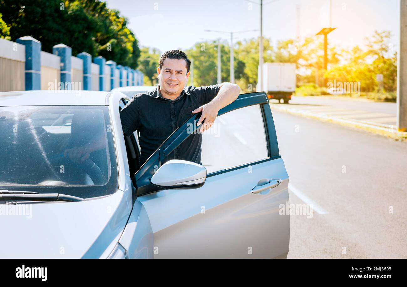 Smiling driver leaning on the car door. happy driver leaning on the car ...