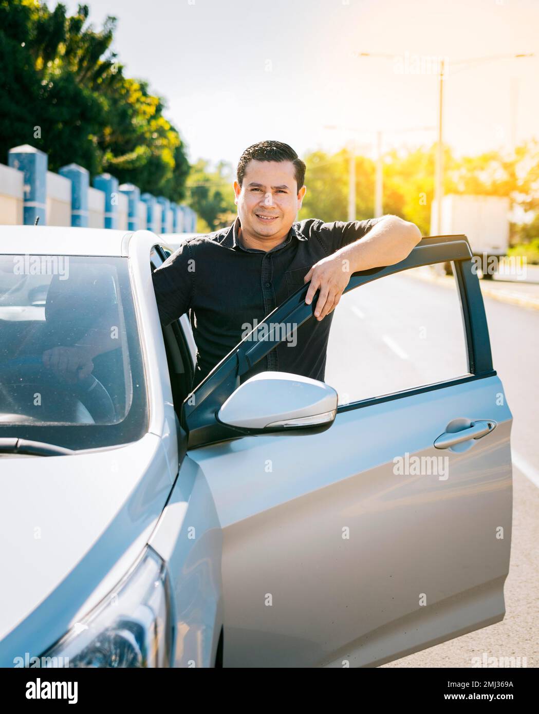 Happy driver leaning on the car door in the street, Smiling driver ...