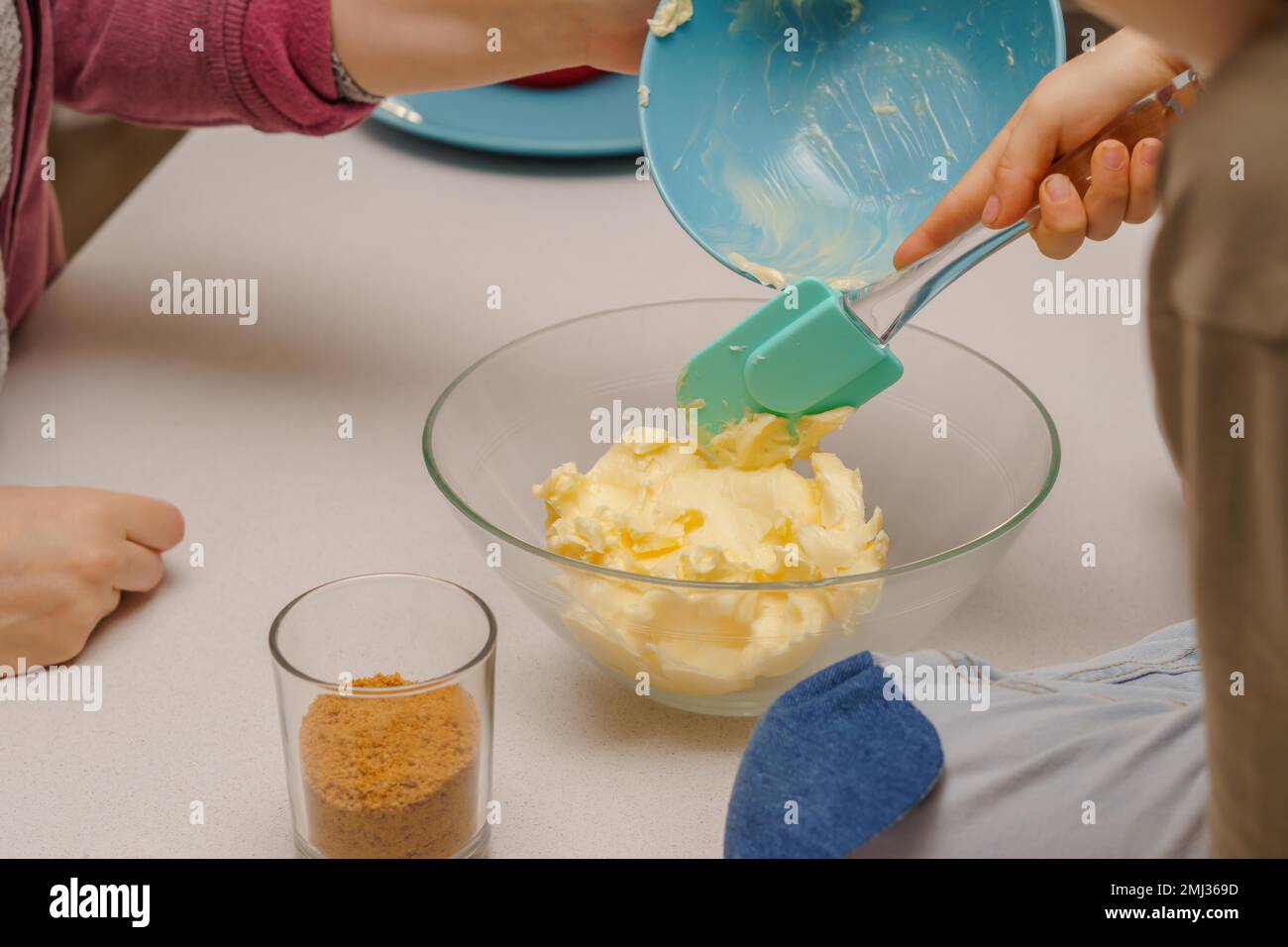 Children with their mother preparing a cake mixing the ingredients ...