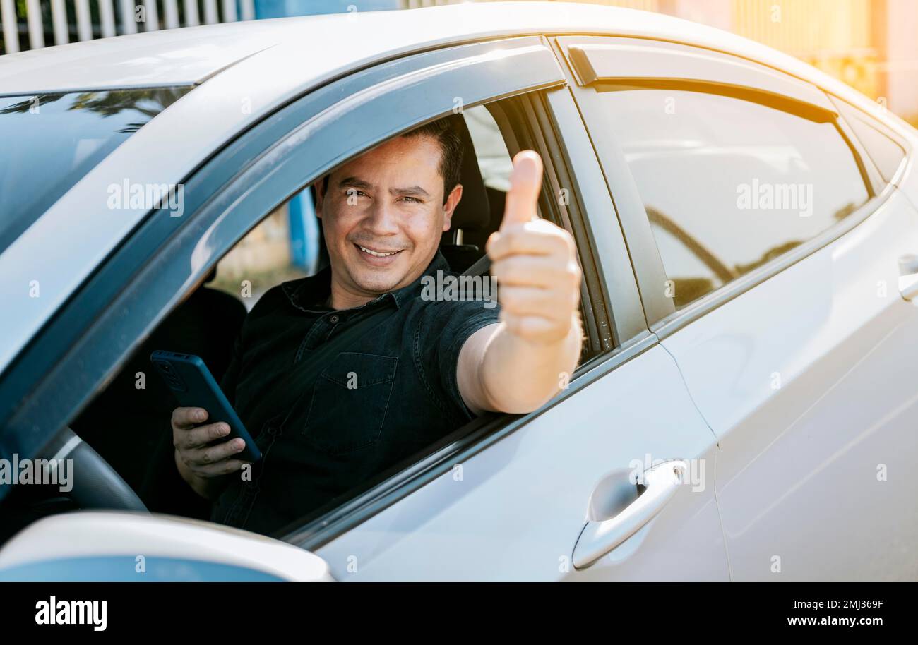 Smiling driver holding cellphone showing thumb up. Driver man showing ...