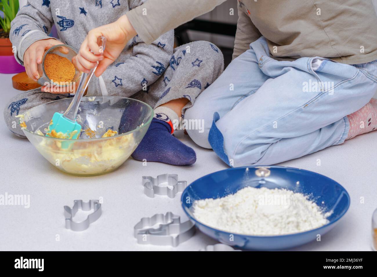 Children on a table mixing the ingredients to prepare a cake Stock ...
