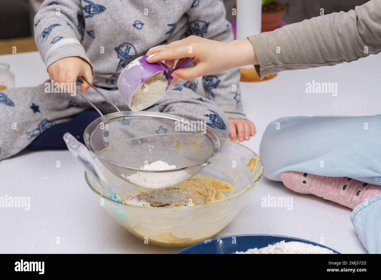 Children on a table mixing the ingredients to prepare a cake Stock ...