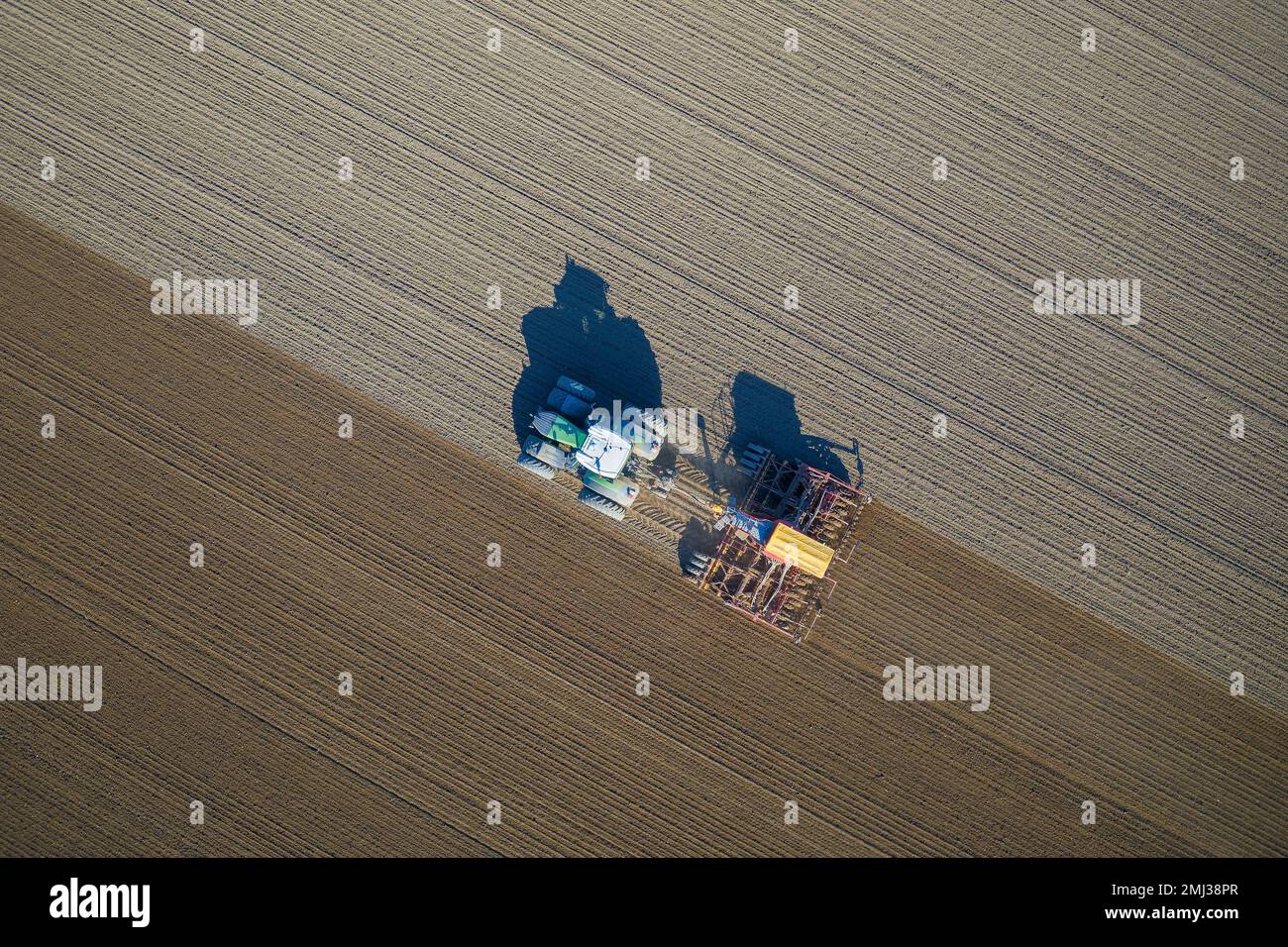 Aerial view over tractor with pneumatic seed drill, agricultural ...