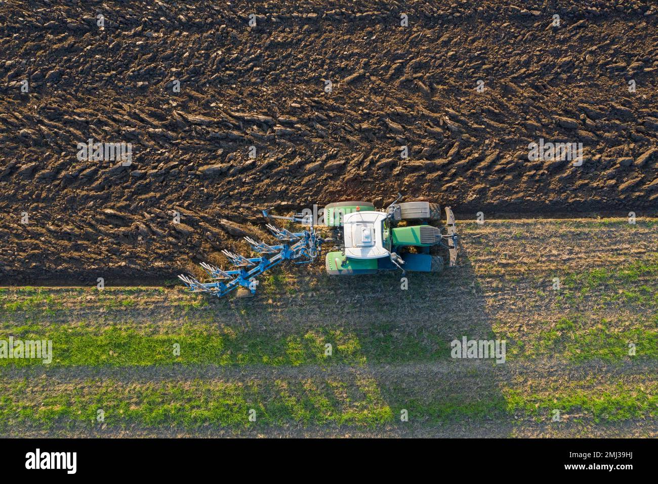 Tractor with plough, agricultural ploughing machine working on a field ...