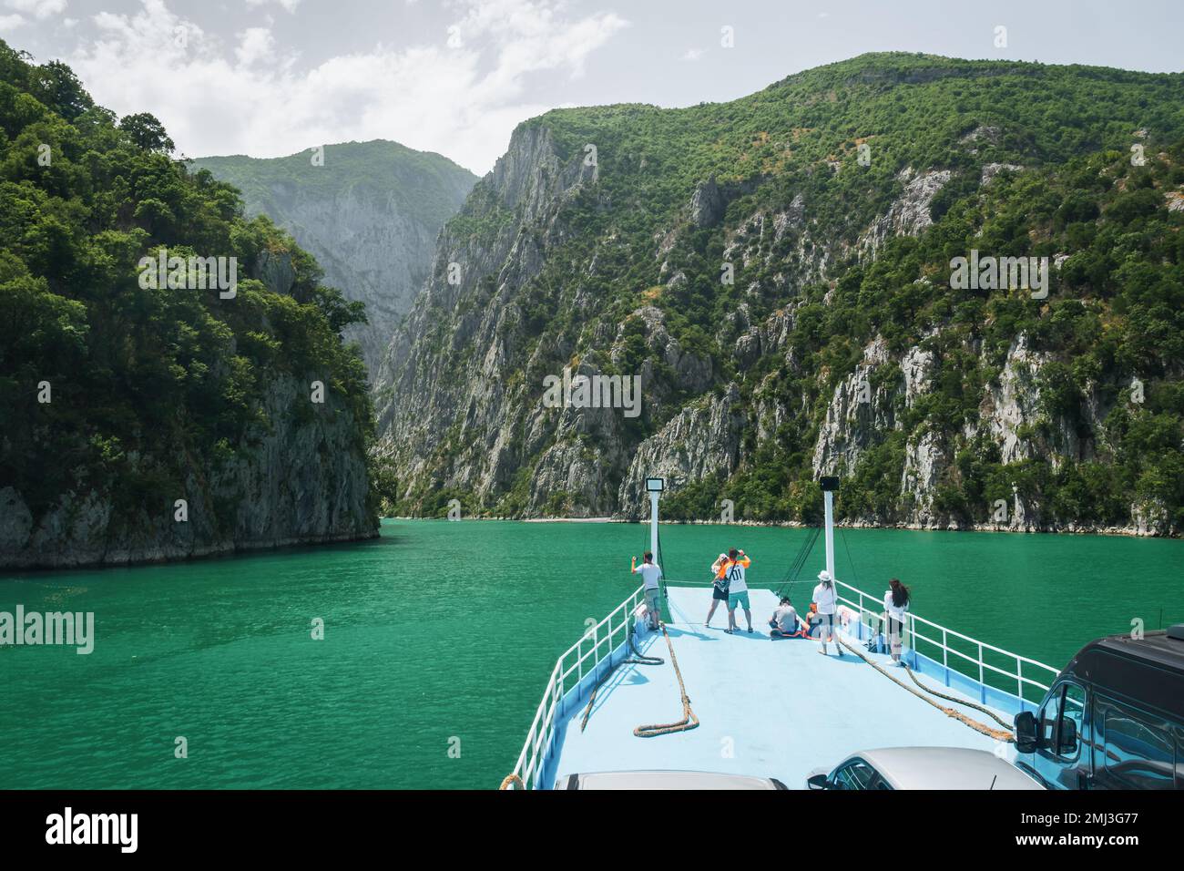View from the ferry on Lake Komani. A tourist boat overtakes the car ...