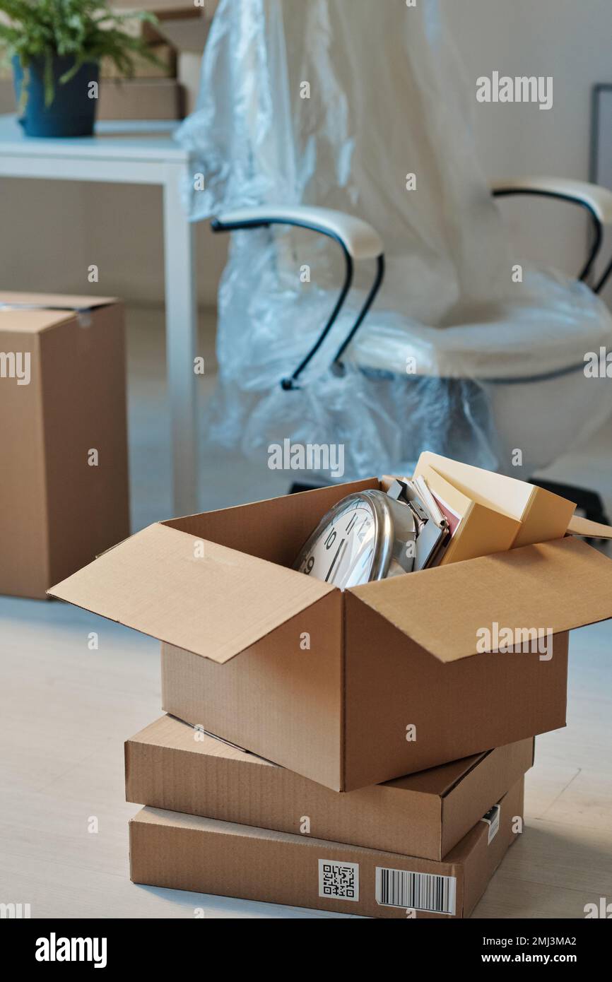 Vertical image of unpacked boxes with office things standing on the ...