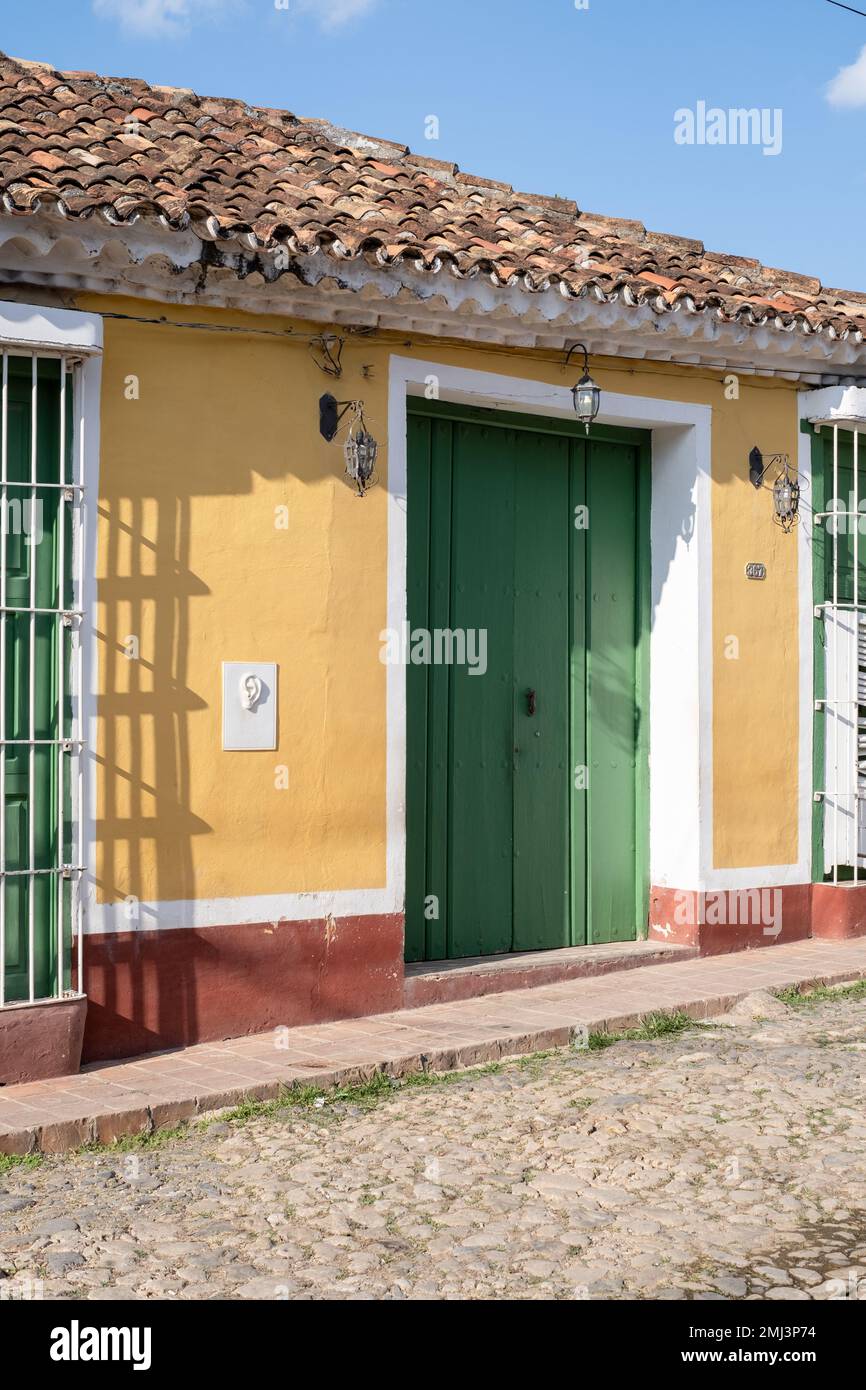 Building with yellow walls and a green door, with a sign featuring a ...
