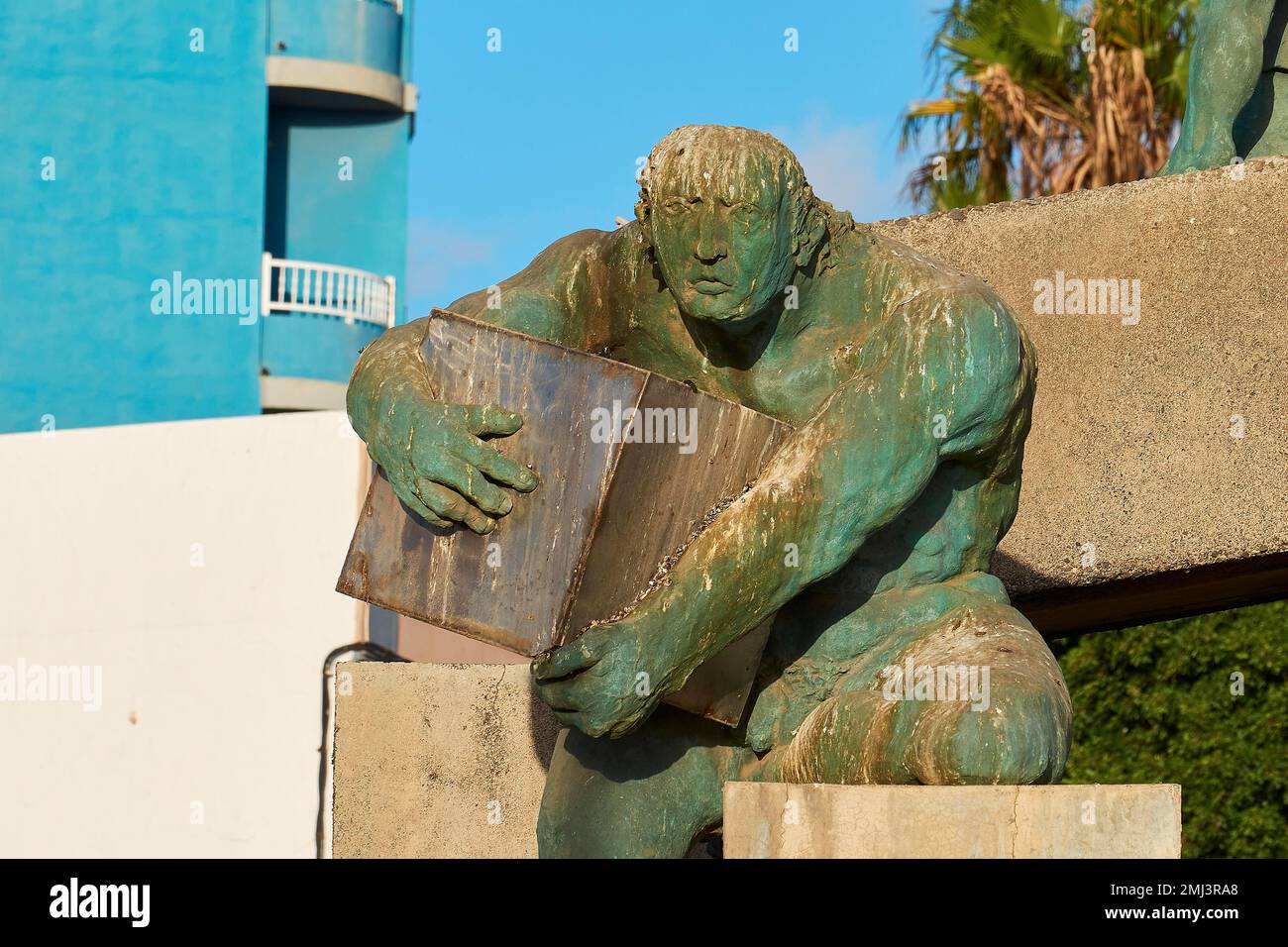 Bronze statue, man with cube, close, blue buildingCapital, Puerto del ...