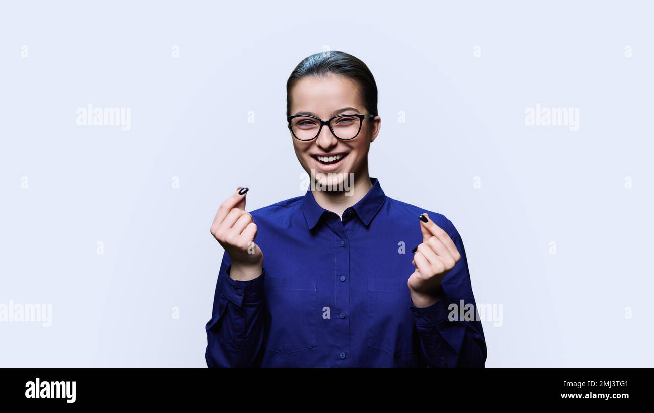 Teenage girl making money gesture, rubbing her fingers, on white ...