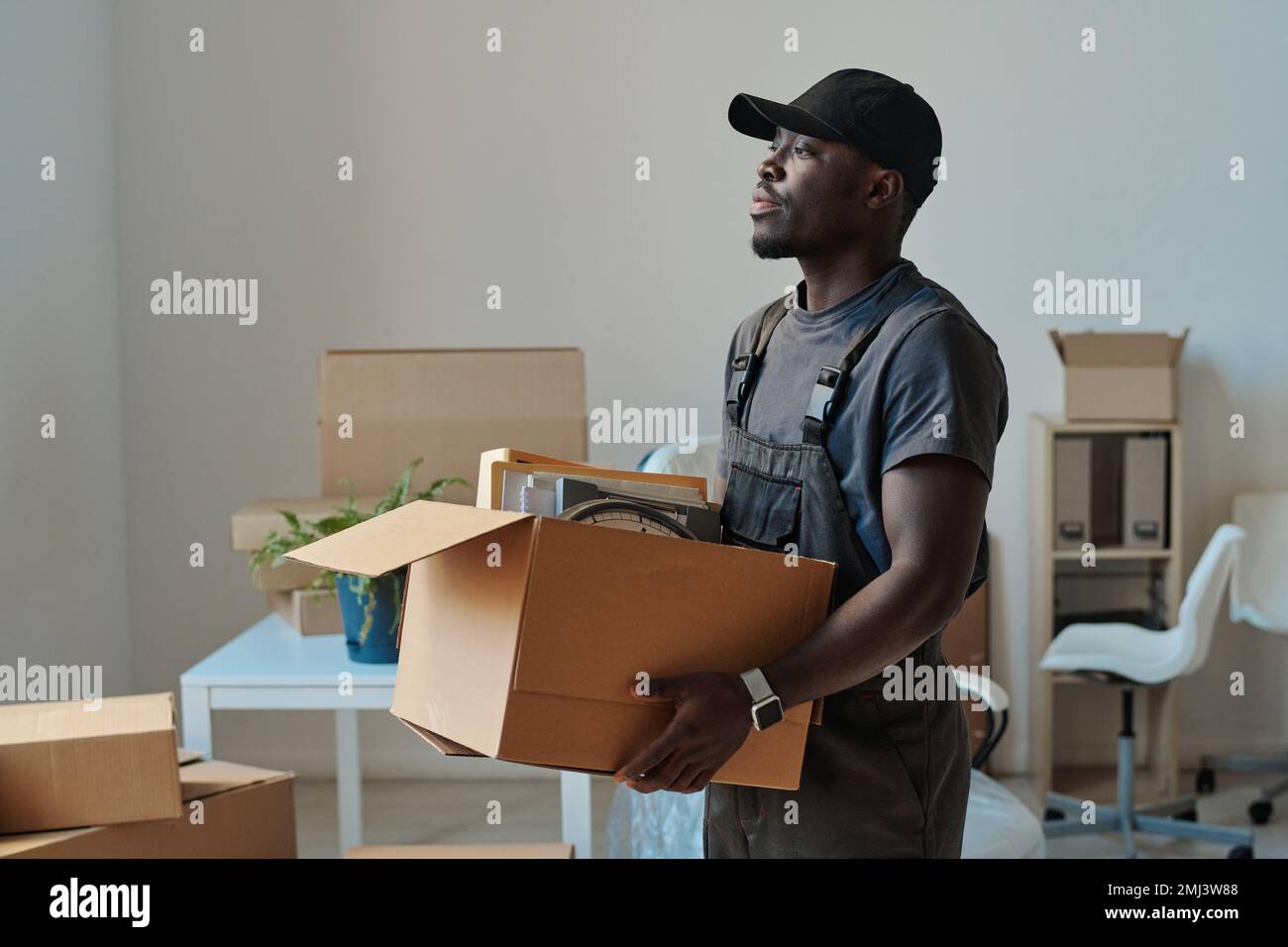 African American worker carrying cardboard boxes with things to a new ...