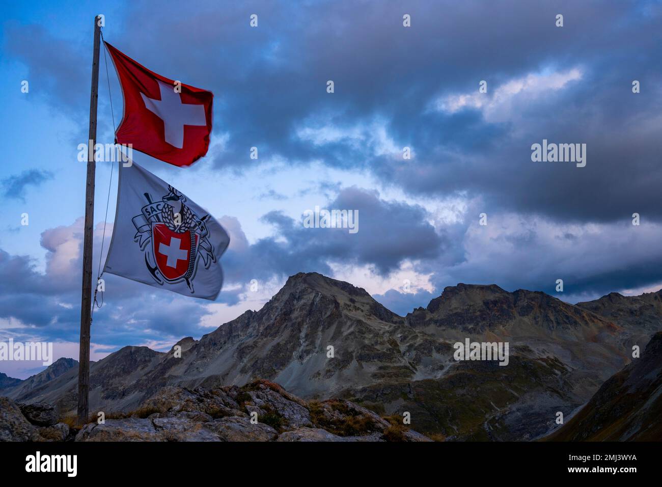 Swiss flag and flag of the SAC with cloudy sky at blue hour and ...