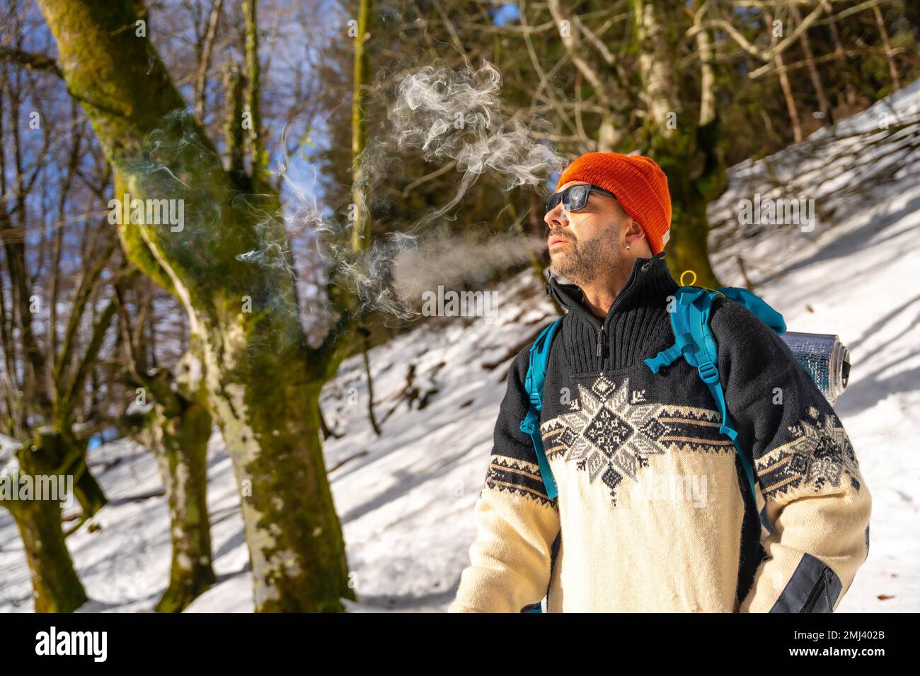 A man smoking a cigarette on a snowy hill in winter, enjoying the cold ...
