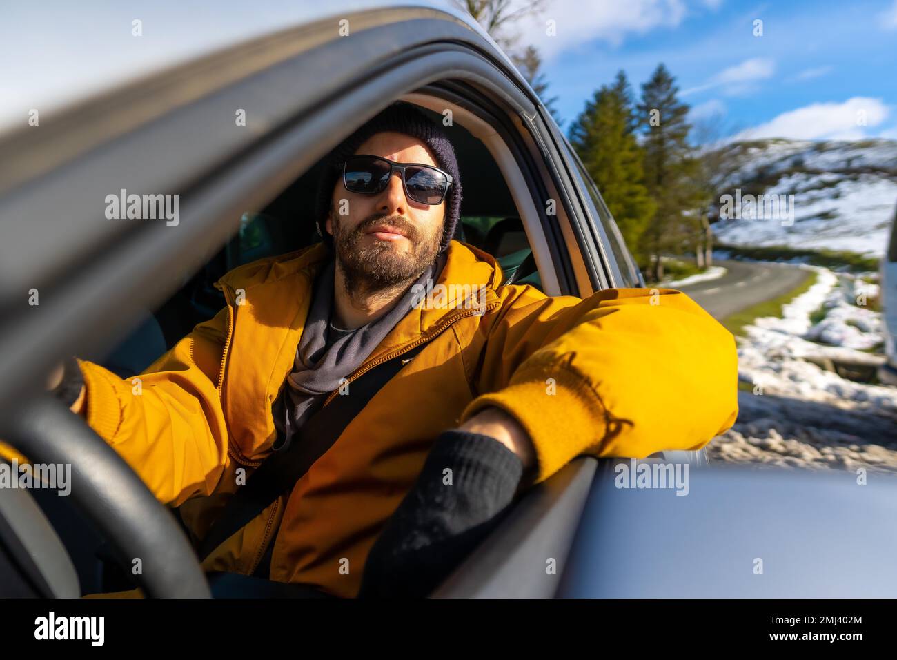 A man inside a gray car on a snowy hill in winter, enjoying driving ...