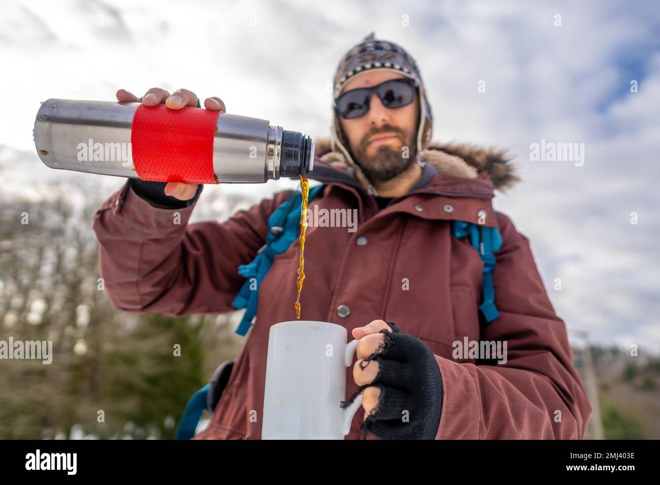 Man having breakfast a hot coffee from a thermos in winter in the snow ...