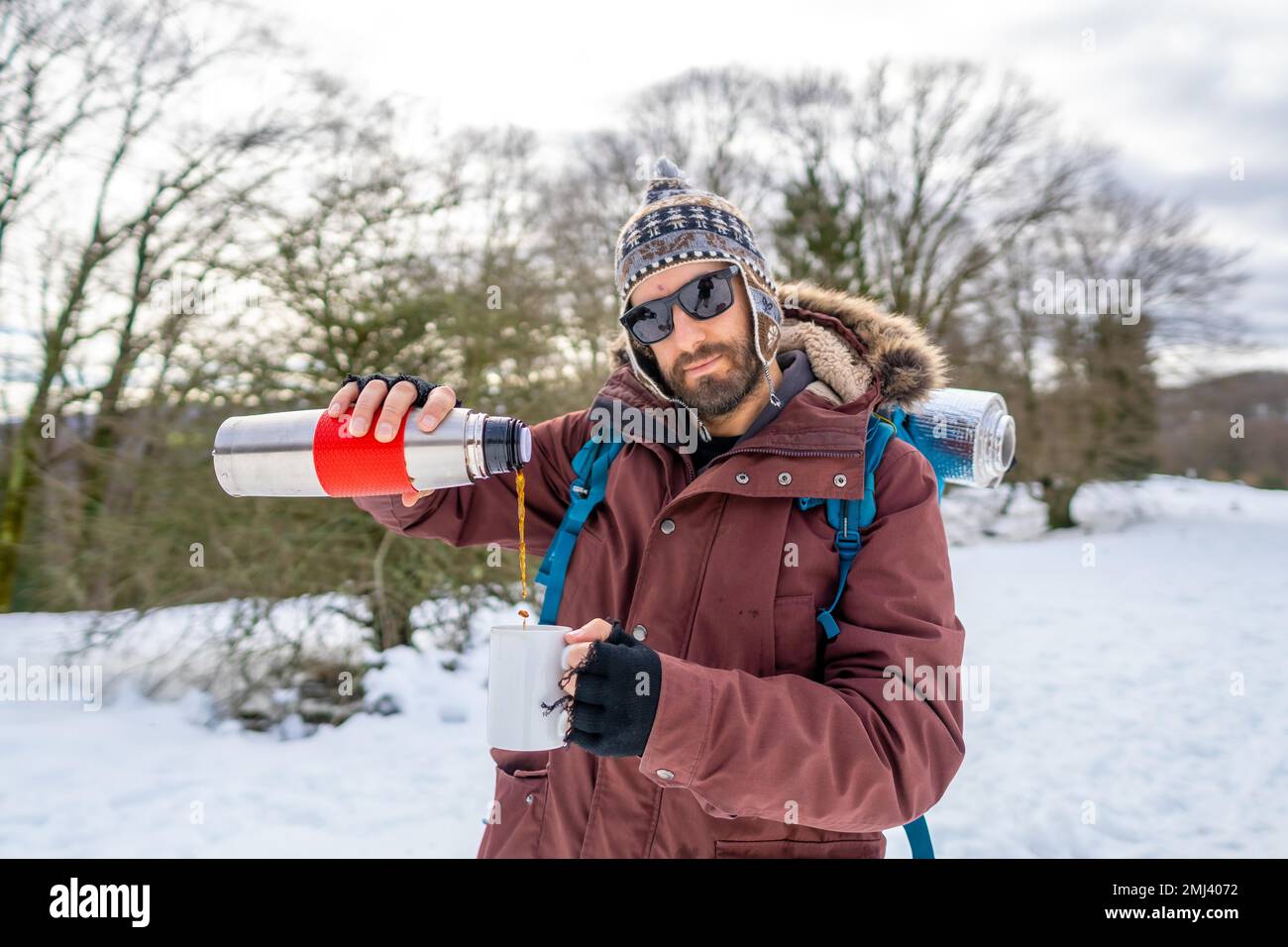 Portrait of man having breakfast a hot coffee from a thermos in winter ...