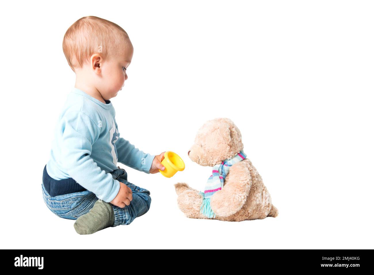 One year old boy feeding his teddy bear, isolated over white background ...