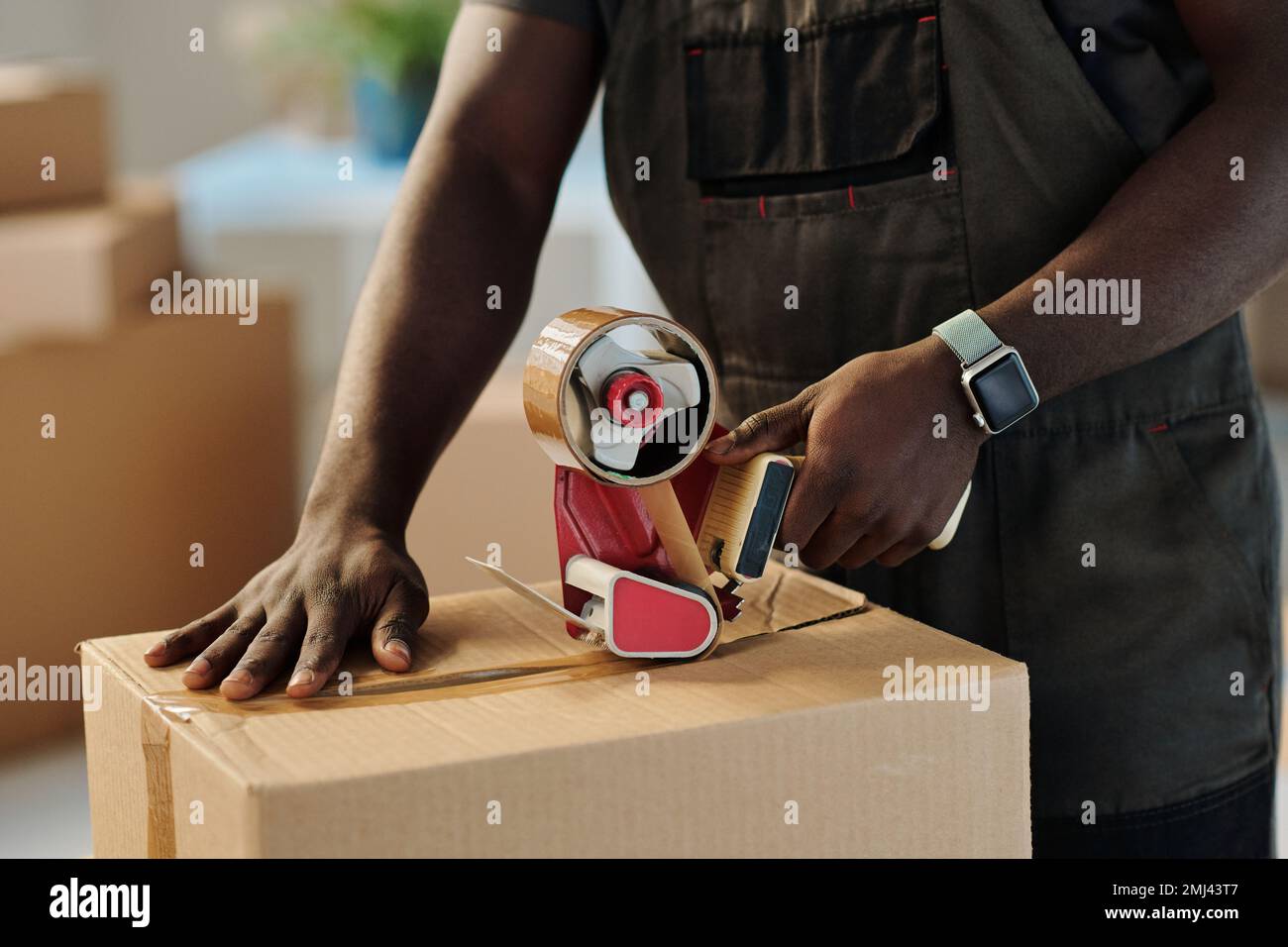 Close-up of worker packing cardboard boxes with adhesive tape while ...