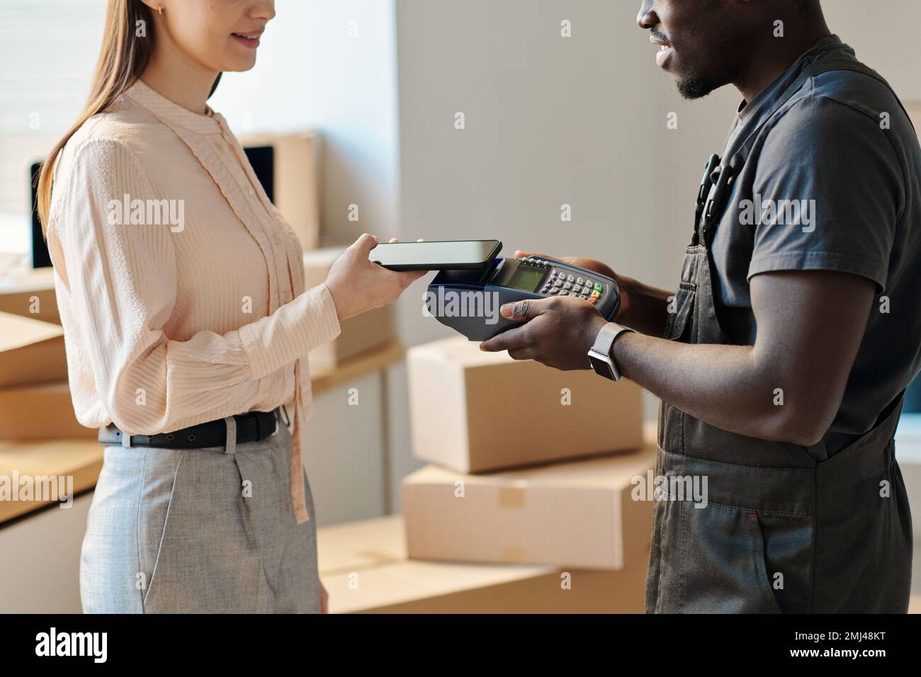 Young woman paying with credit card for moving while loader holding ... Young woman paying with credit card for moving while loader holding ...