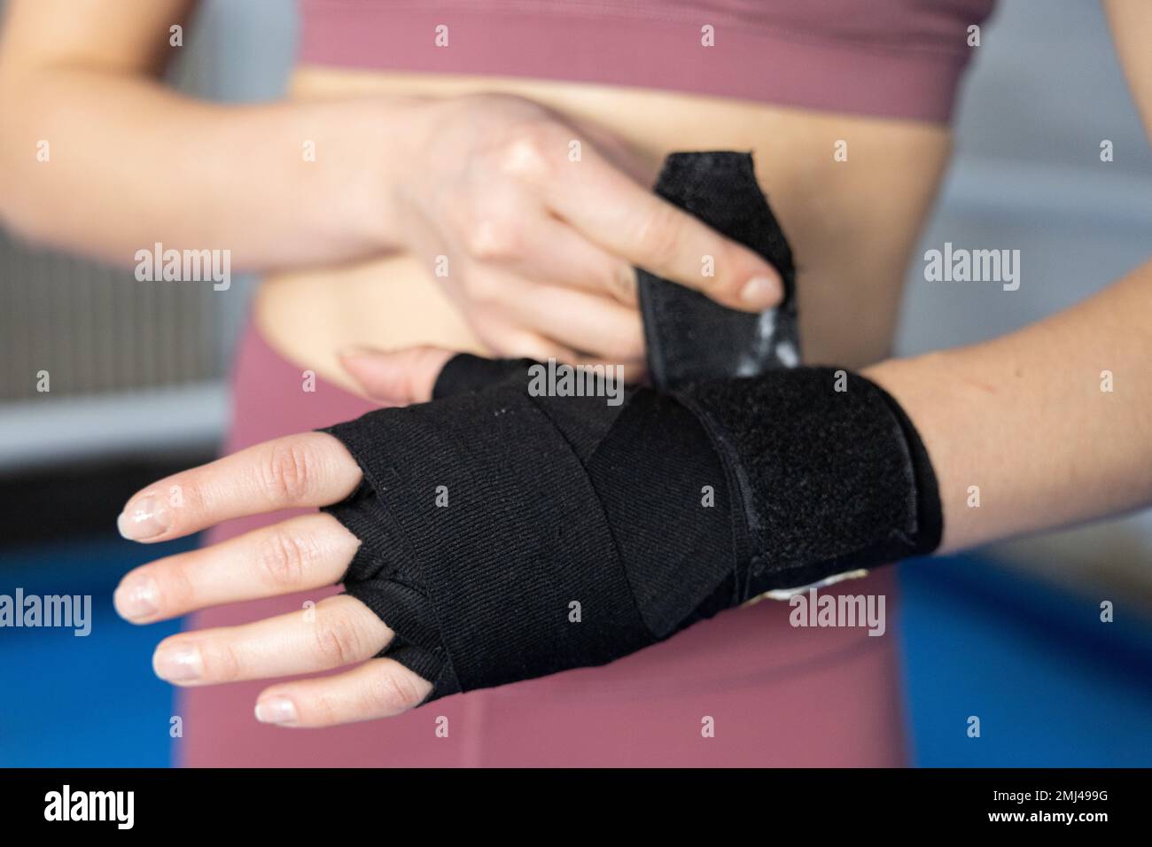 The hands of a boxer girl who bandages her arms for protection before ...
