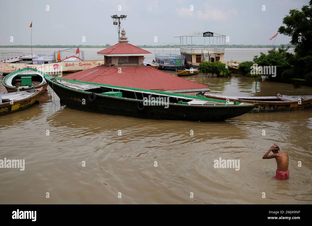 A man takes a ritualistic bath in the waters of the swollen River ...